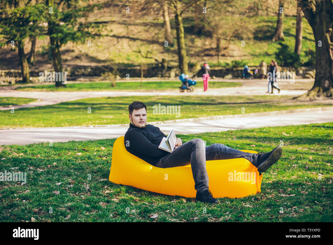 book reading concept. man in city park on inflatable mattress. spring ...