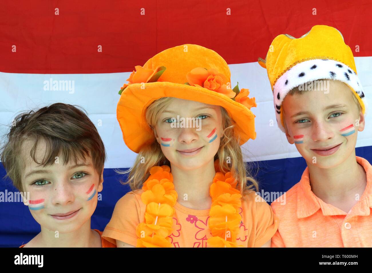 Three dutch children dressed up in orange in front of flag of the ...