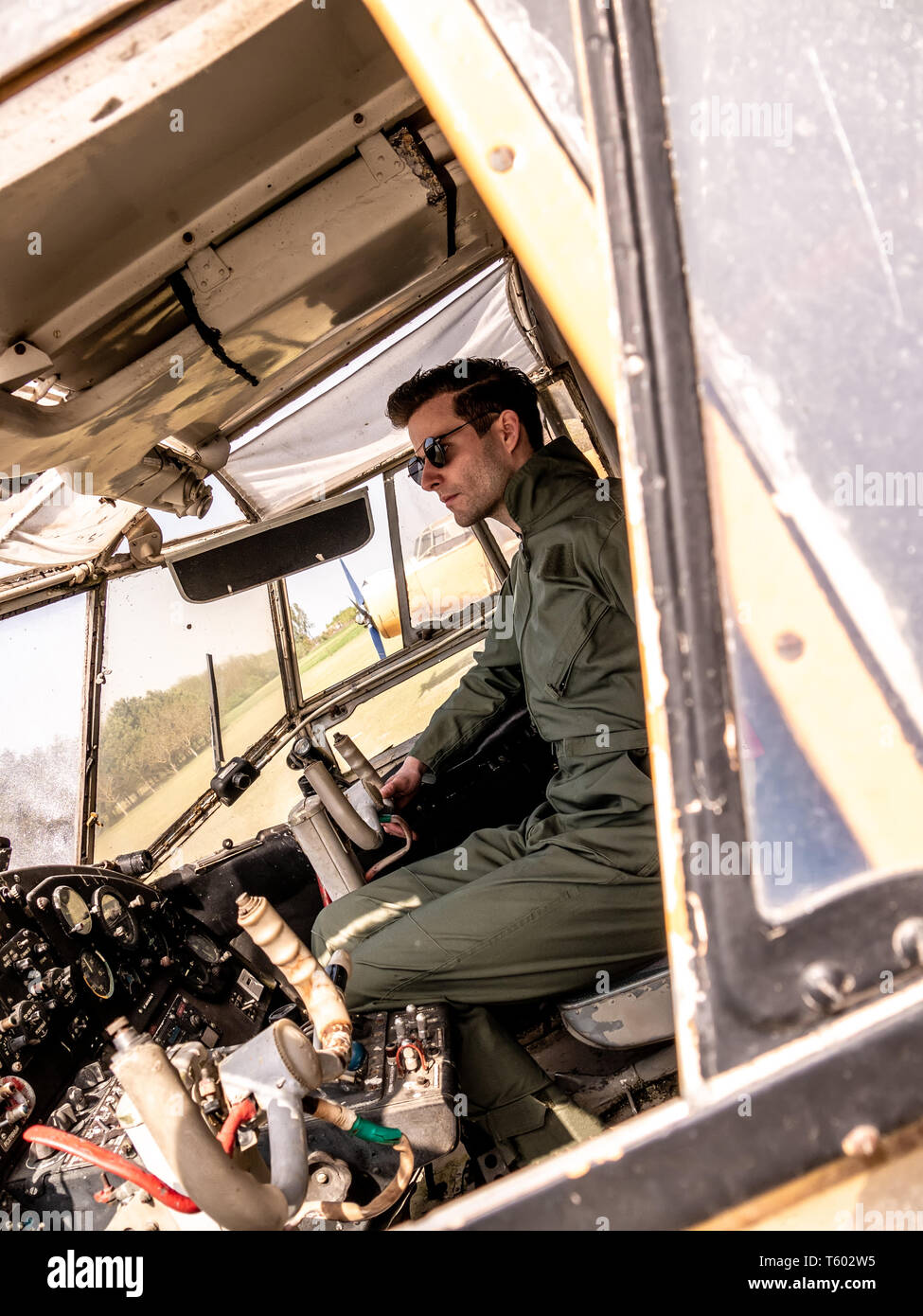 A handsome young man pilot in a green overall sitting in the cockpit of ...