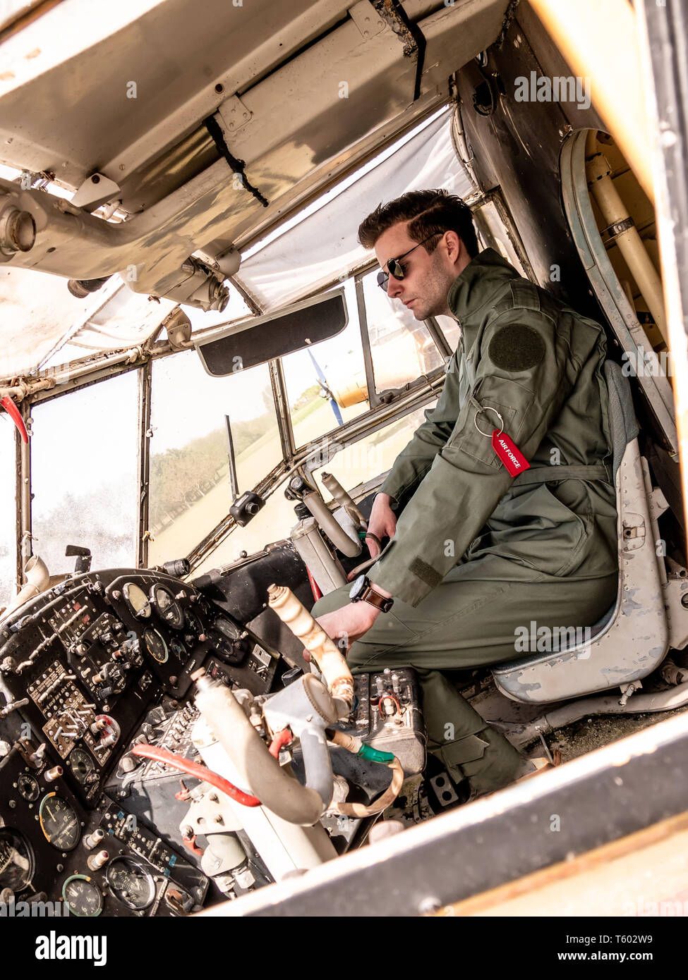 A handsome young man pilot in a green overall sitting in the cockpit of ...