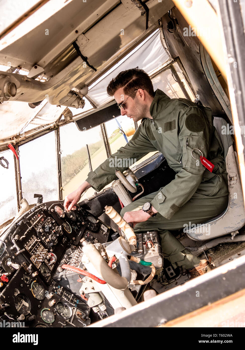 A handsome young man pilot in a green overall sitting in the cockpit of ...
