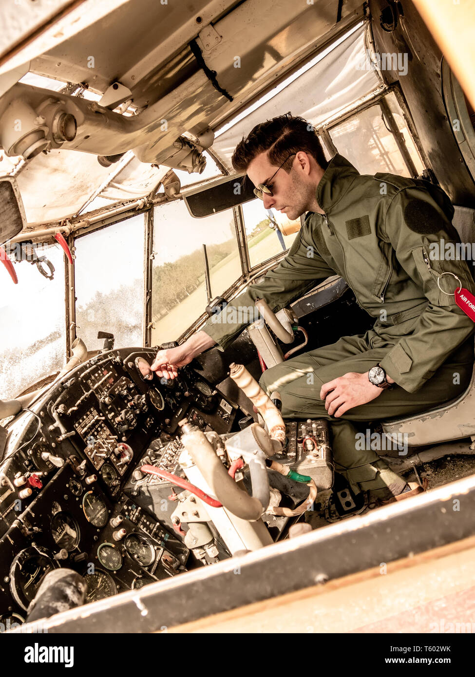 A handsome young man pilot in a green overall sitting in the cockpit of ...