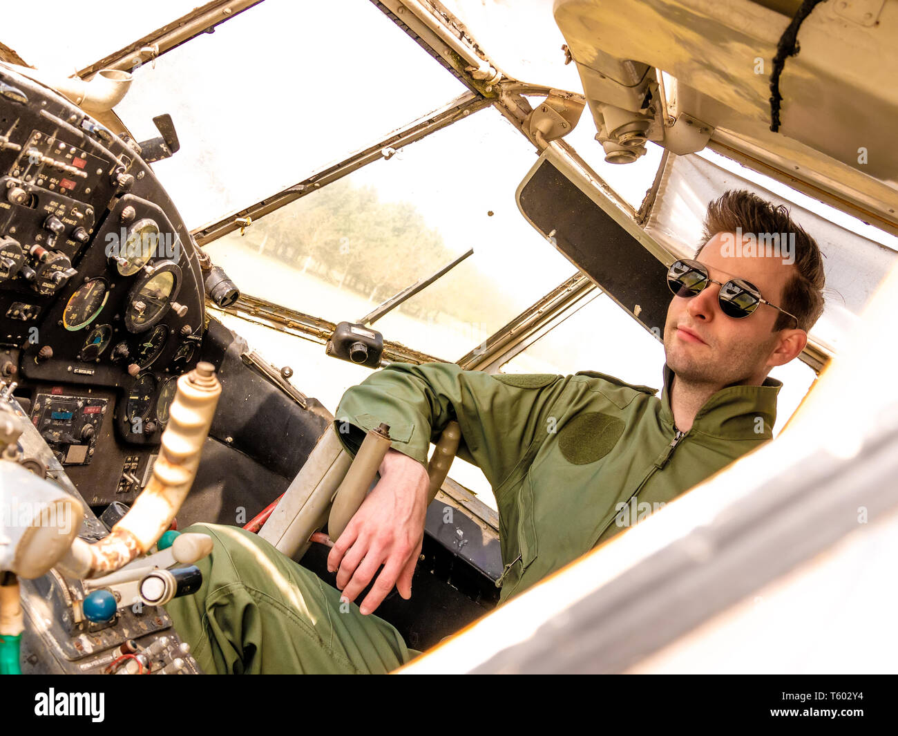 A handsome young man pilot in a green overall sitting in the cockpit of ...