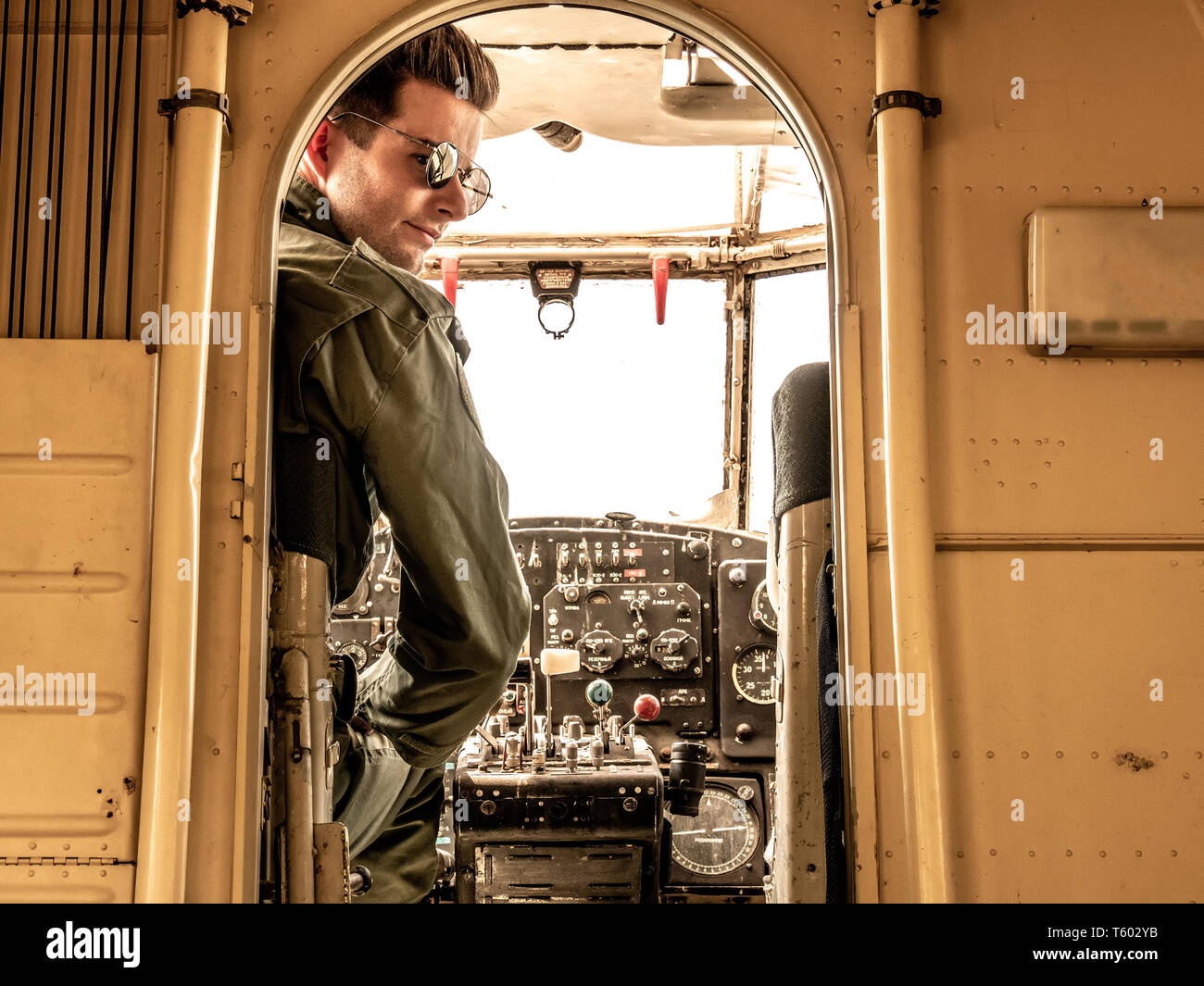 A handsome young man pilot in a green overall sitting in the cockpit of ...