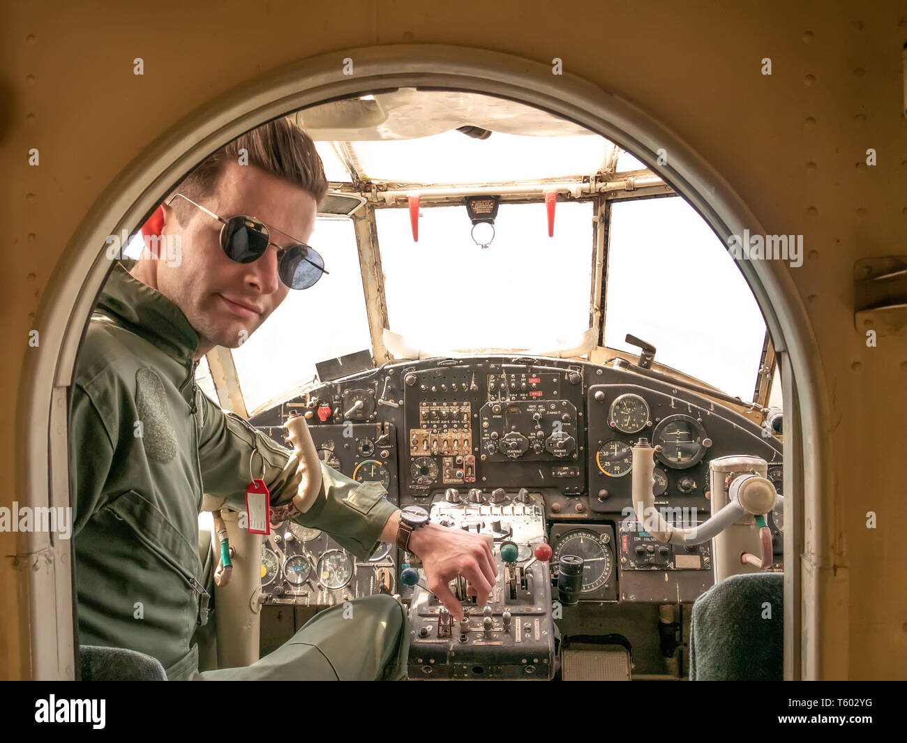 A handsome young man pilot in a green overall sitting in the cockpit of ...