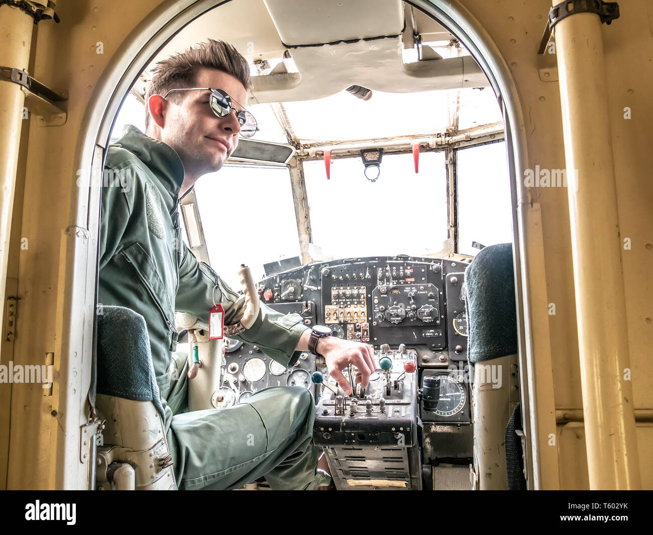 A handsome young man pilot in a green overall sitting in the cockpit of ...