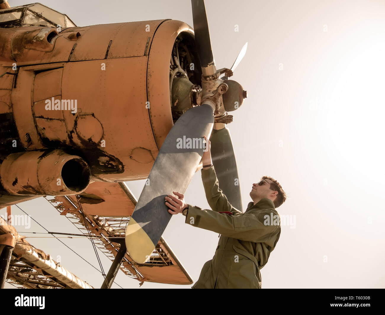 A handsome young man pilot in a green overall standing next to the ...