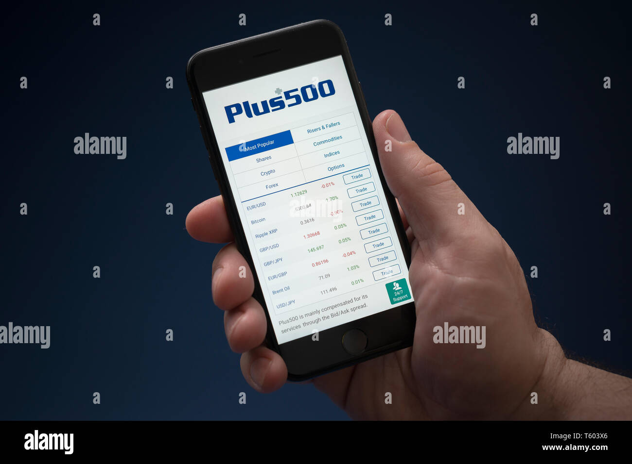 A man looks at his iPhone which displays the Plus500 logo (Editorial ...