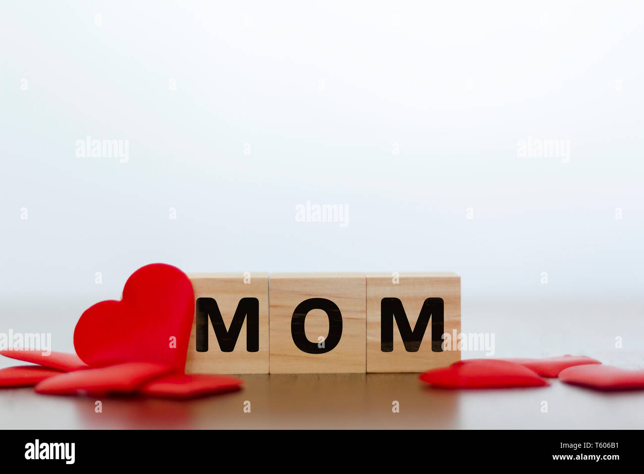 MOM word written on wooden cubes with red hearts around. Mother's day ...