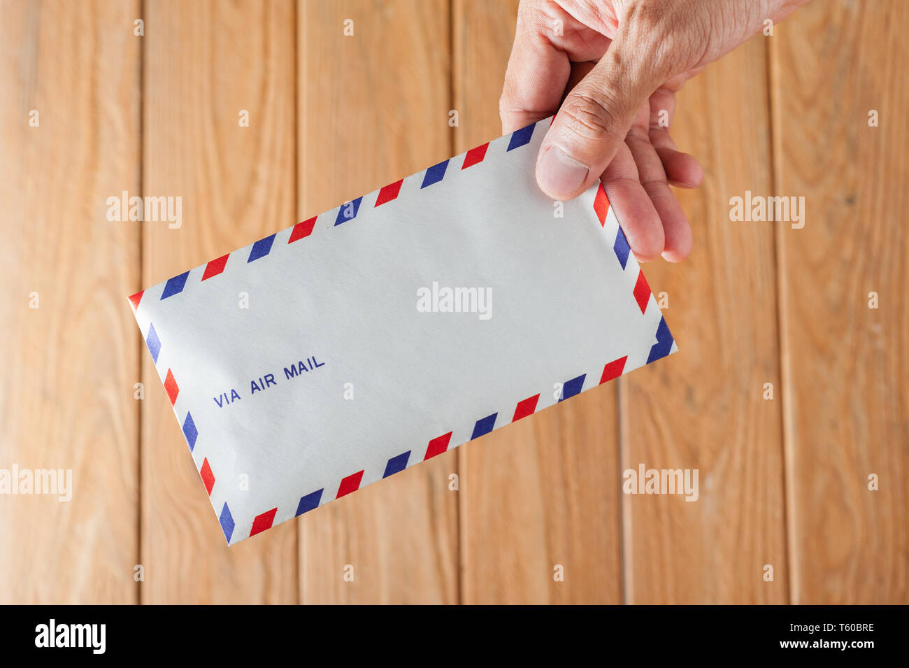 air mail envelope in hand over wood background Stock Photo - Alamy