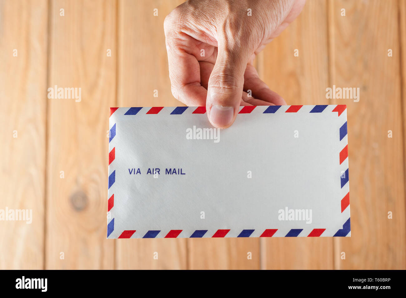 air mail envelope in hand over wood background Stock Photo - Alamy