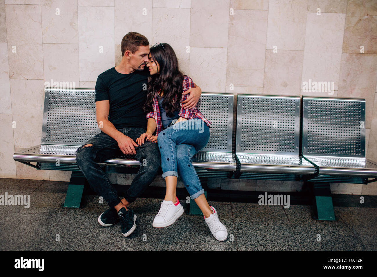 Young man and woman use underground. Couple in subway. Sitting on bench ...
