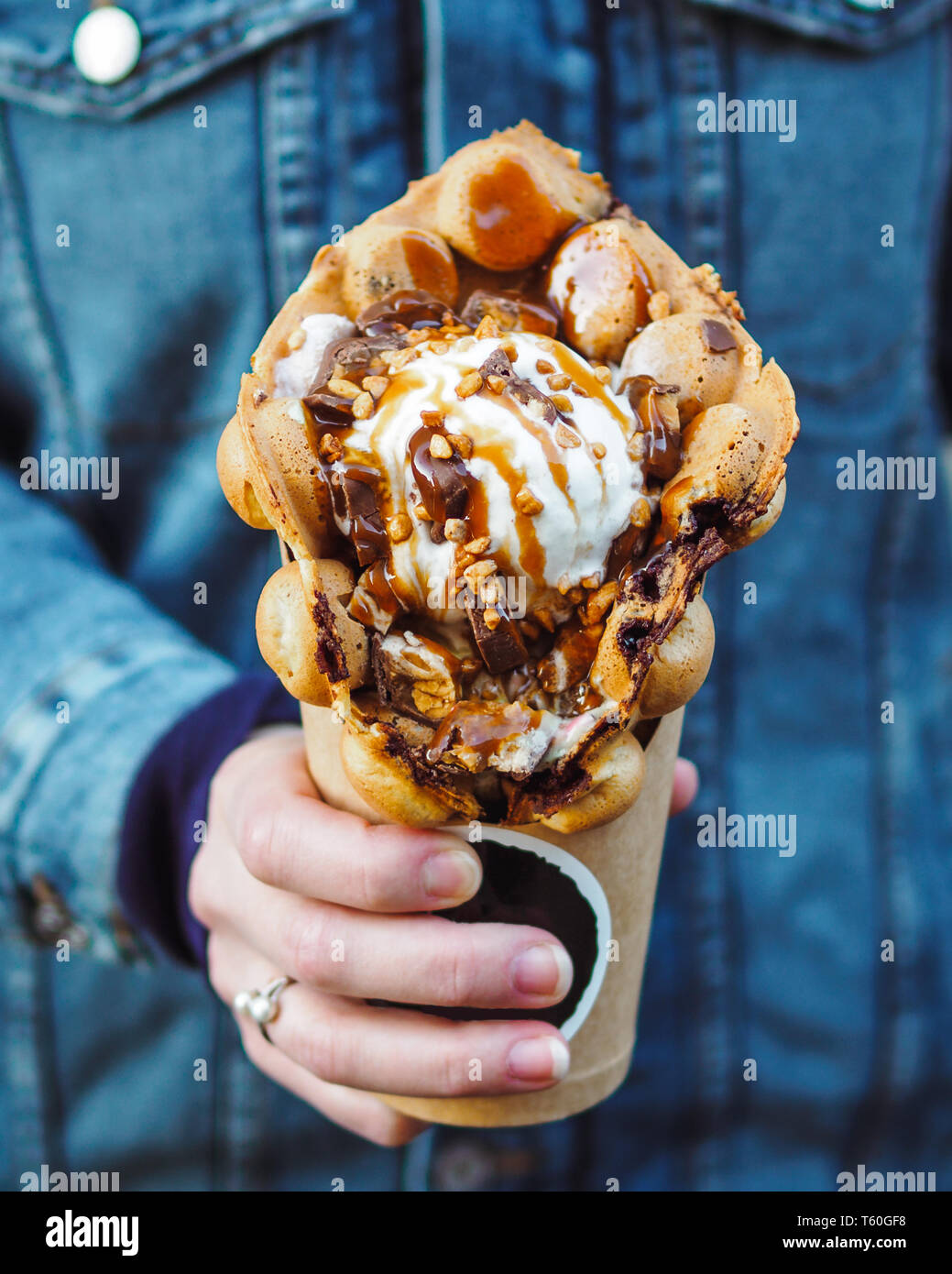 Hong Kong waffles in female hand. Girl in denim jacket hold delicious ...