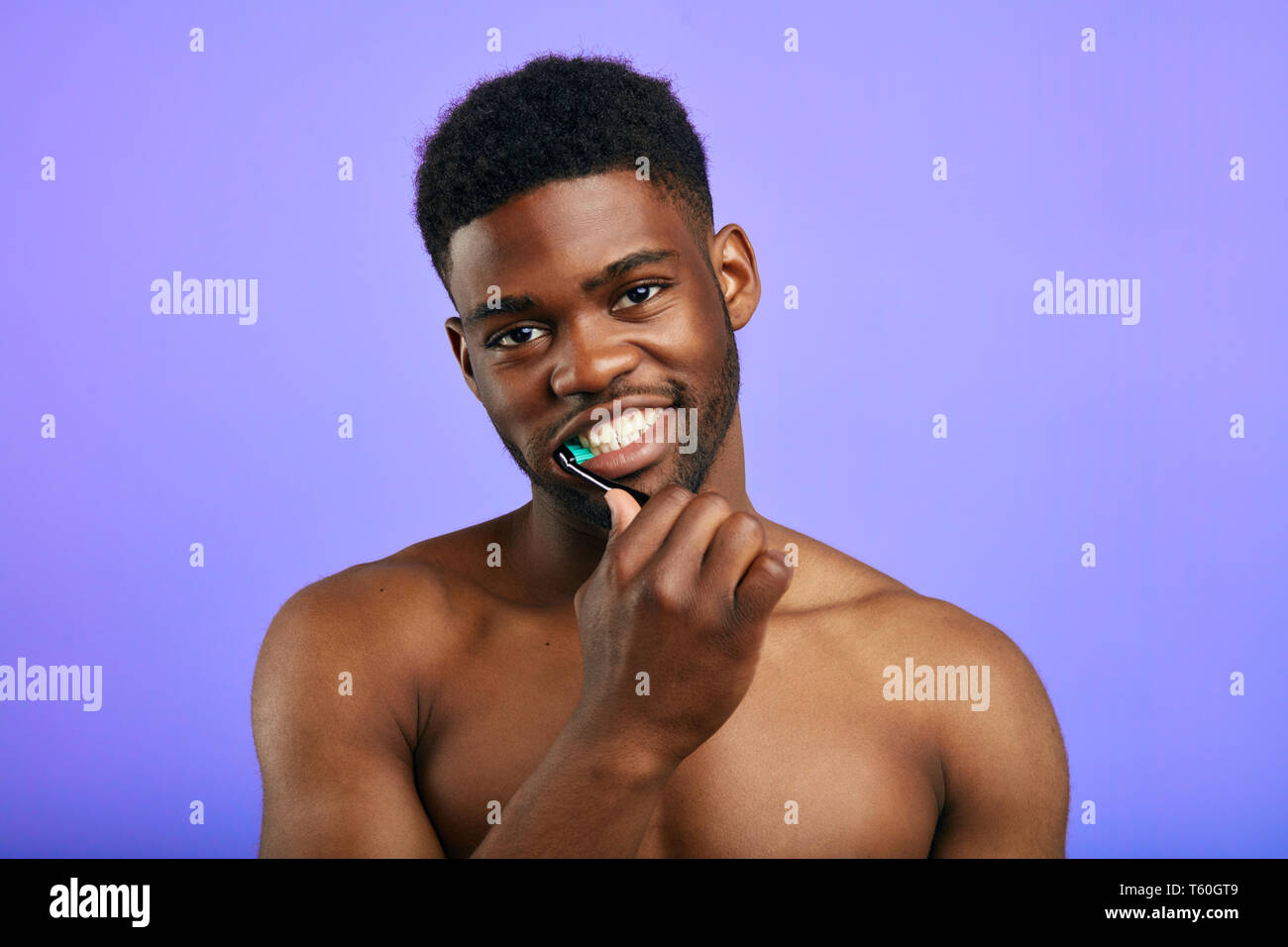 smiling young man with toothbrush in his mouth, isolated in the blue ...