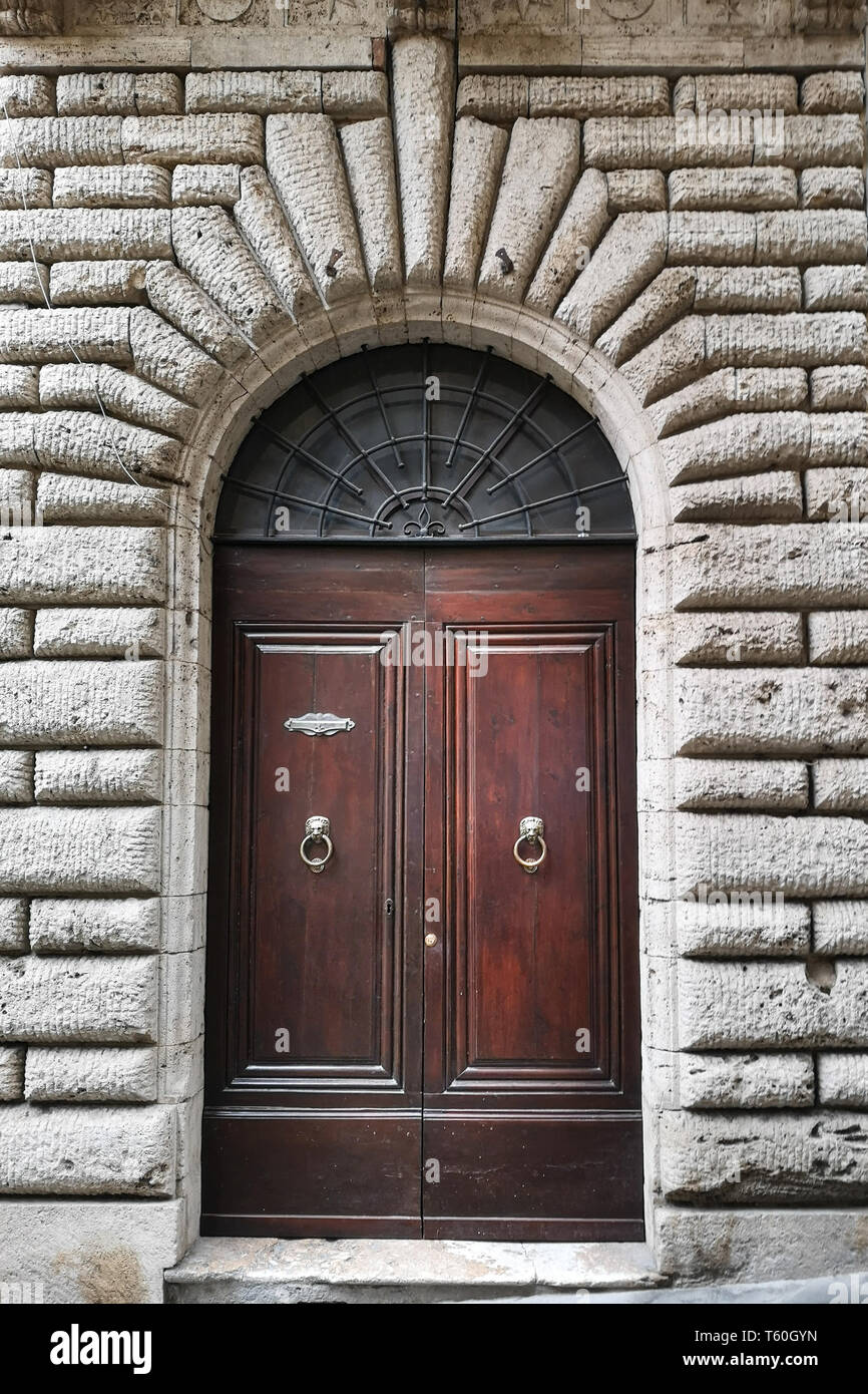 Ancient wooden portal with carved stone arch of an Italian medieval ...