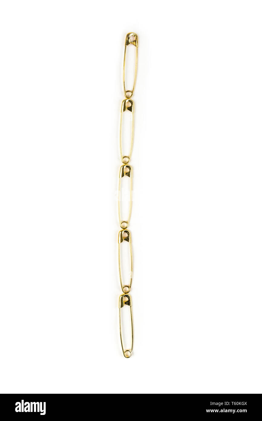 Five gold safety pins pushed together in a line on a white background ...