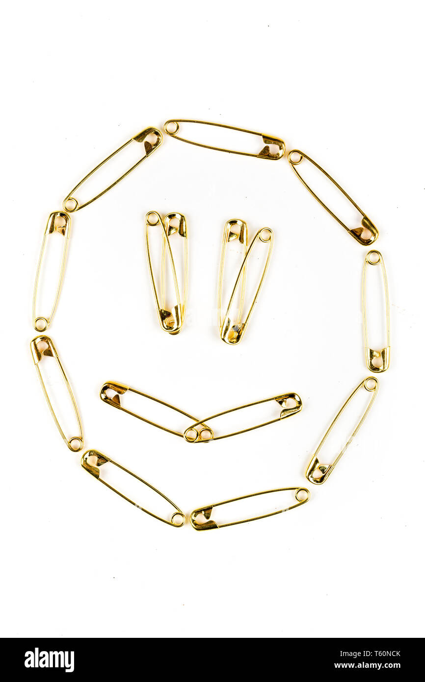 Happy face of gold colored safety pins on a white background Stock ...