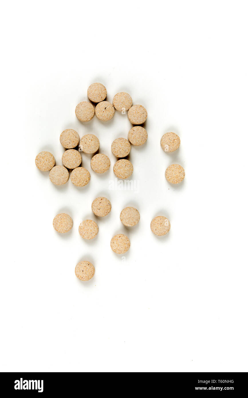 Scattered tan colored pills over a white background Stock Photo - Alamy