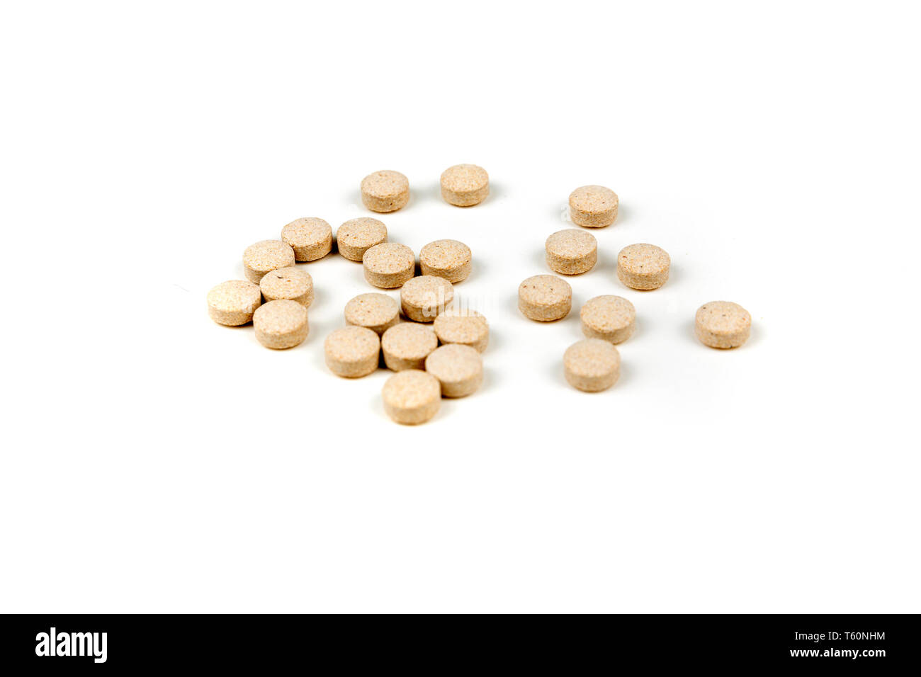 Scattered tan colored pills over a white background Stock Photo - Alamy