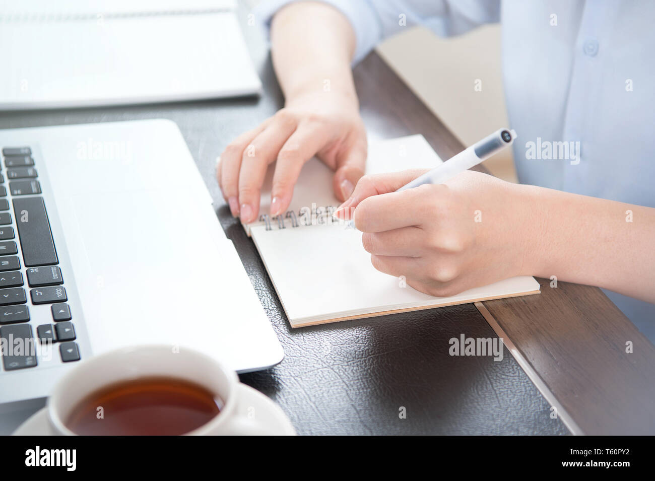 Business concept. Woman takes note for project with laptop and report ...
