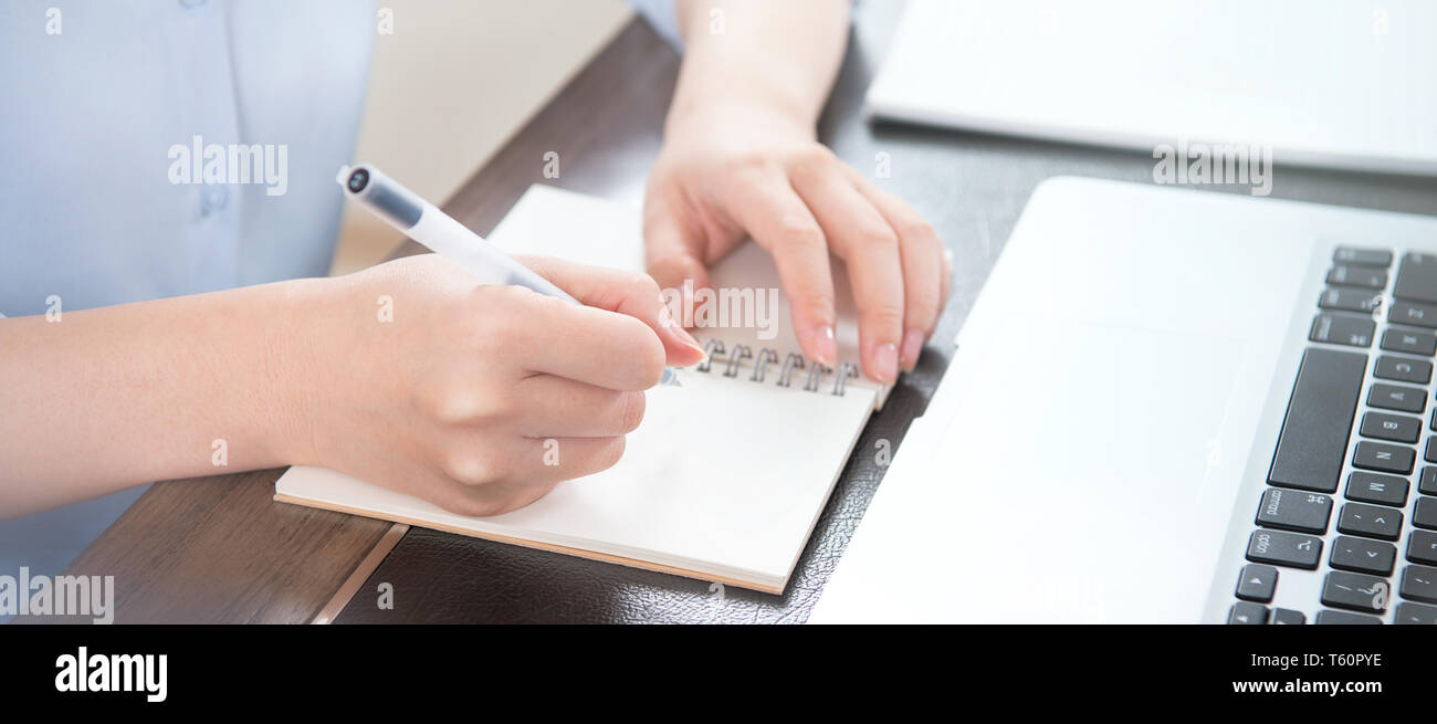 Business concept. Woman takes note for project with laptop and report ...