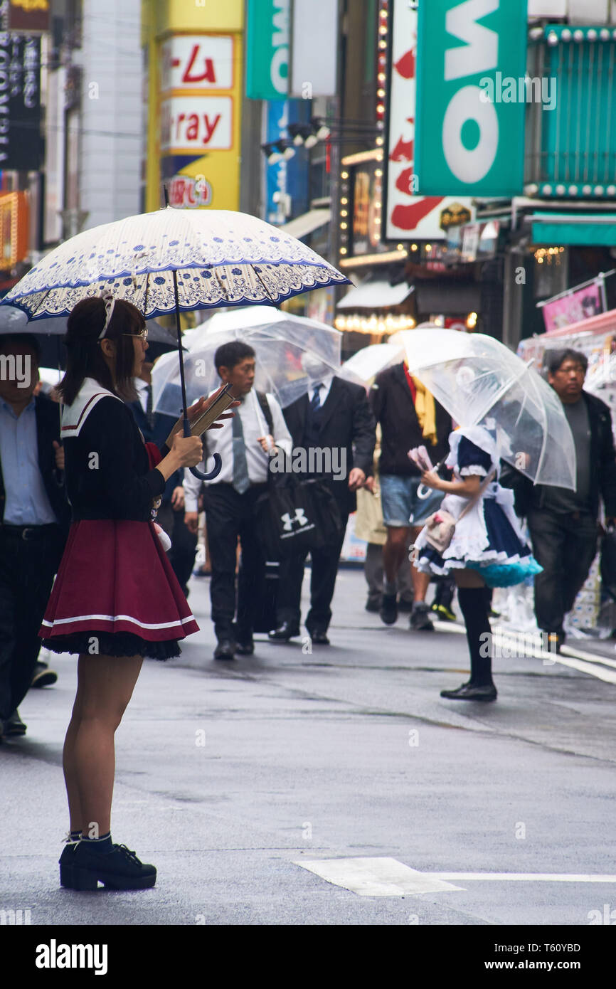 Two women dressed as maids advertise to businessmen for nearby Maid ...