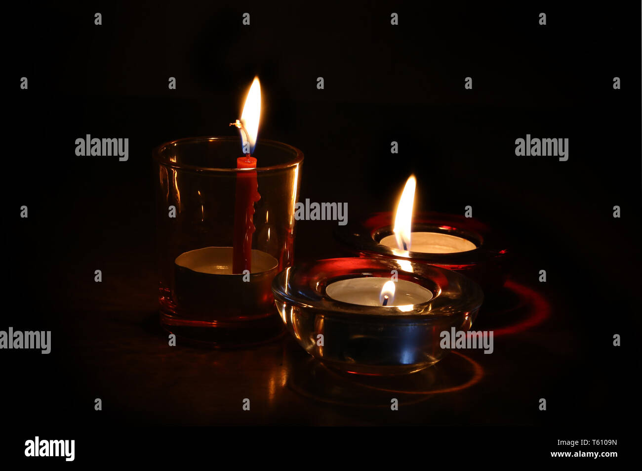 Three bright burning candles in the dark Stock Photo - Alamy