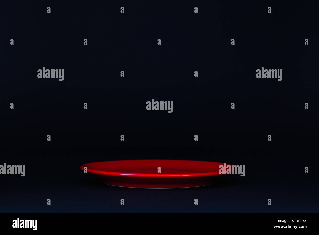 Empty red plate on the black background Stock Photo - Alamy