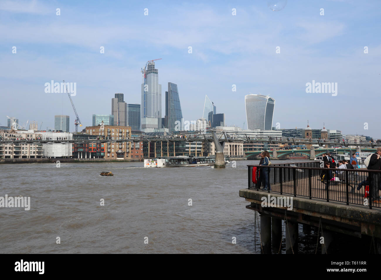 A couple look out across the River Thames with City of London ...