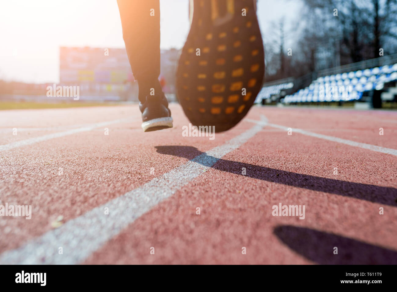Photo from behind close-up of athlete's feet running around stadium on ...