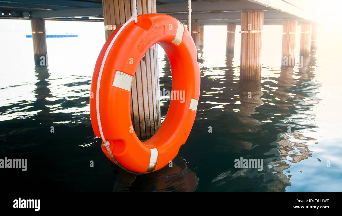 Closeup photo of red saving ring hanging wooden pier. Safety on sea ...