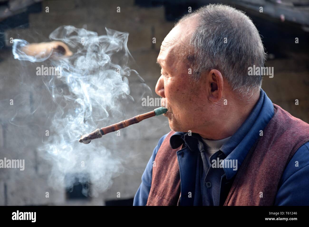 GUIZHOU PROVINCE, CHINA – CIRCA APRIL 2019: An old man puffed away on ...