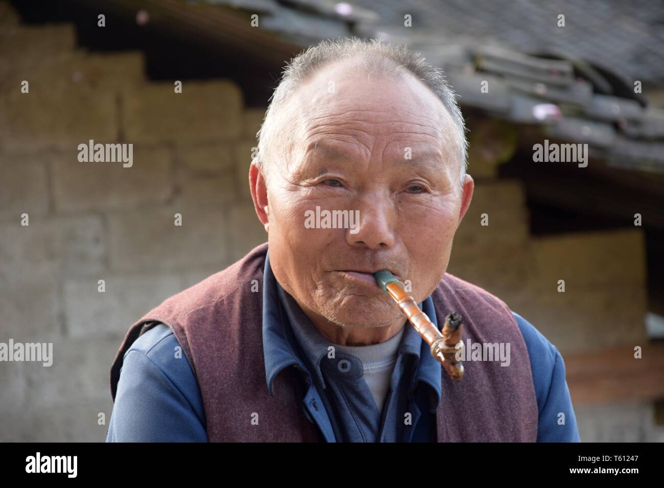 GUIZHOU PROVINCE, CHINA – CIRCA APRIL 2019: An old man puffed away on ...