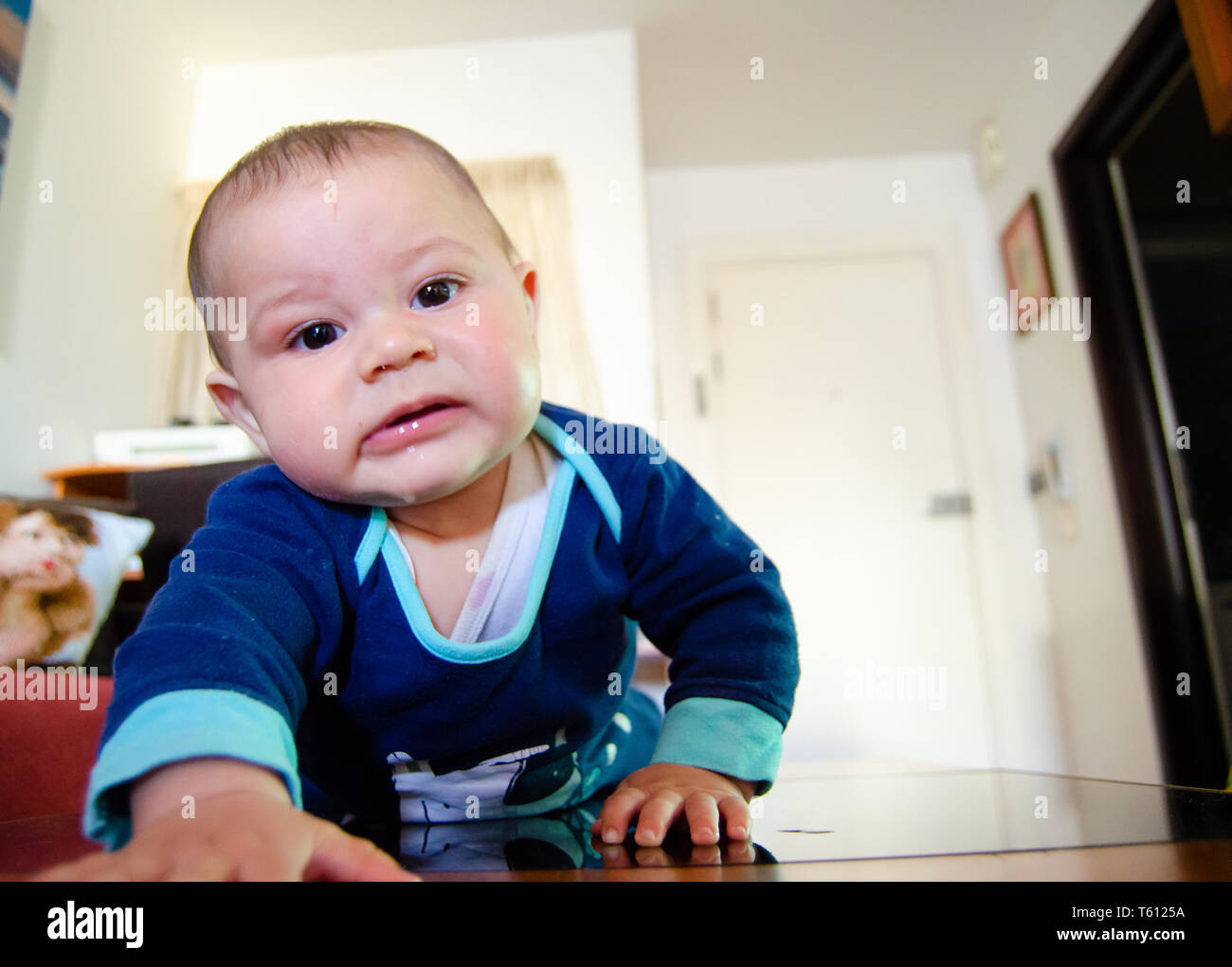cute six months old baby boy drooling on the flor and making funny ...
