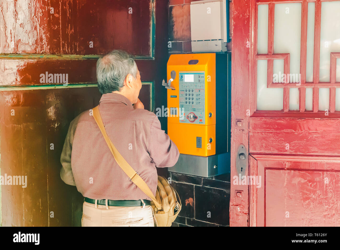 Old Taiwanese man (elderly man) using a payphone to call his relative ...