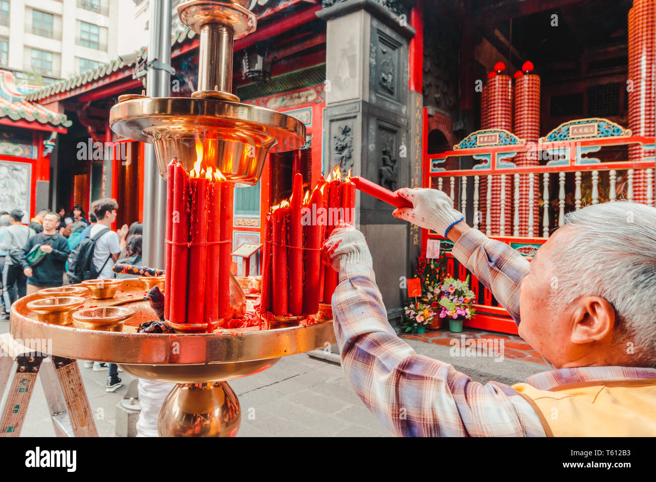 Staff at Longshan Temple lighting candle for visitor to burn the ...