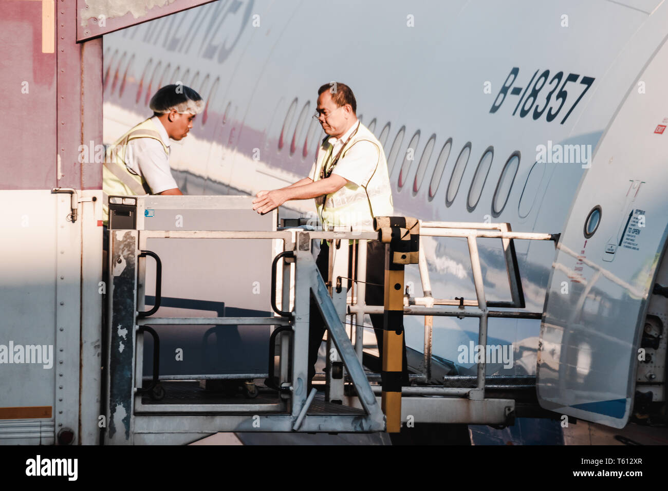 Asian ground crew loading food and supply into a departing aircraft ...