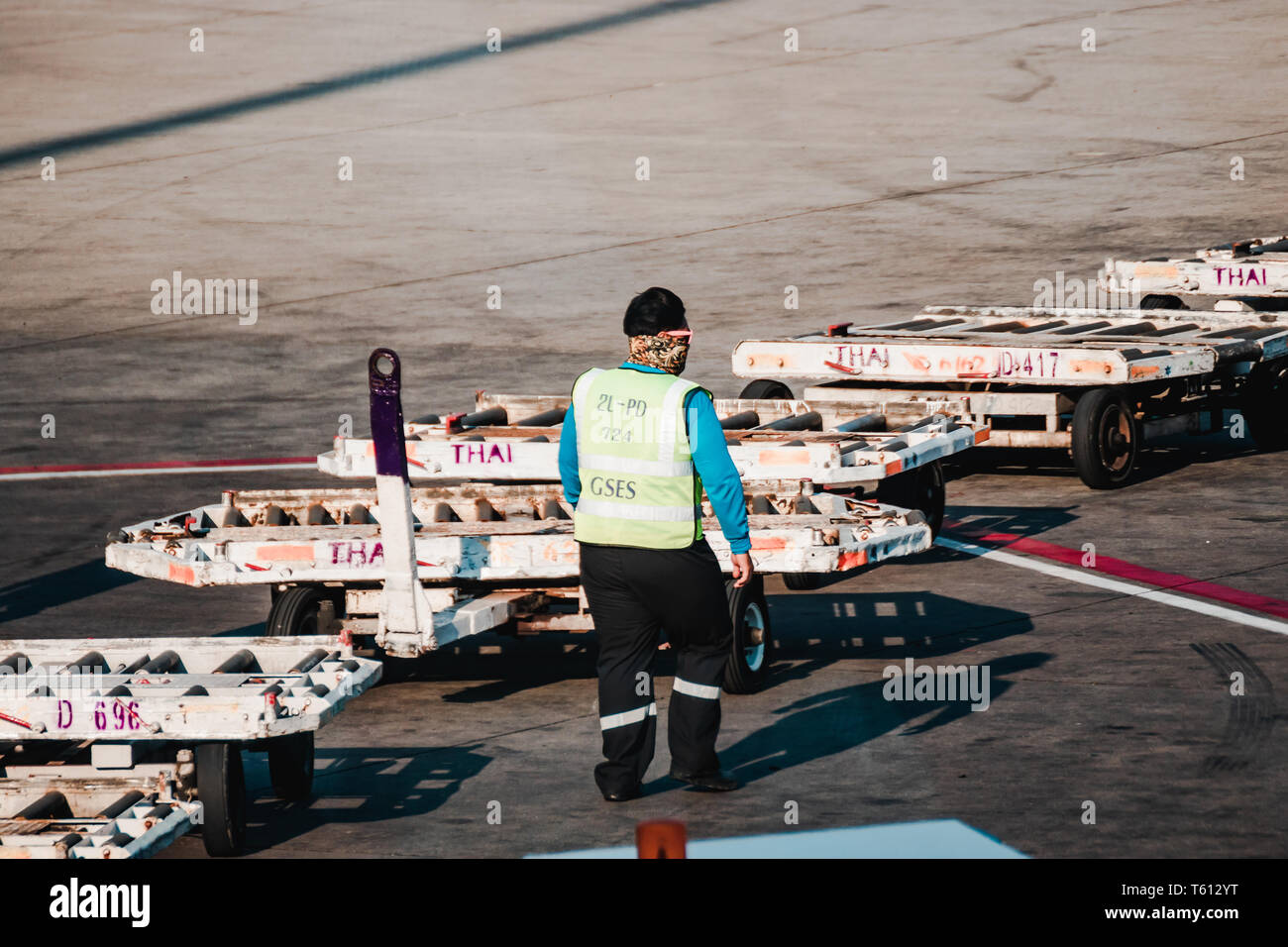 Asian ground crew transporting cargo to be loaded into an aircraft ...