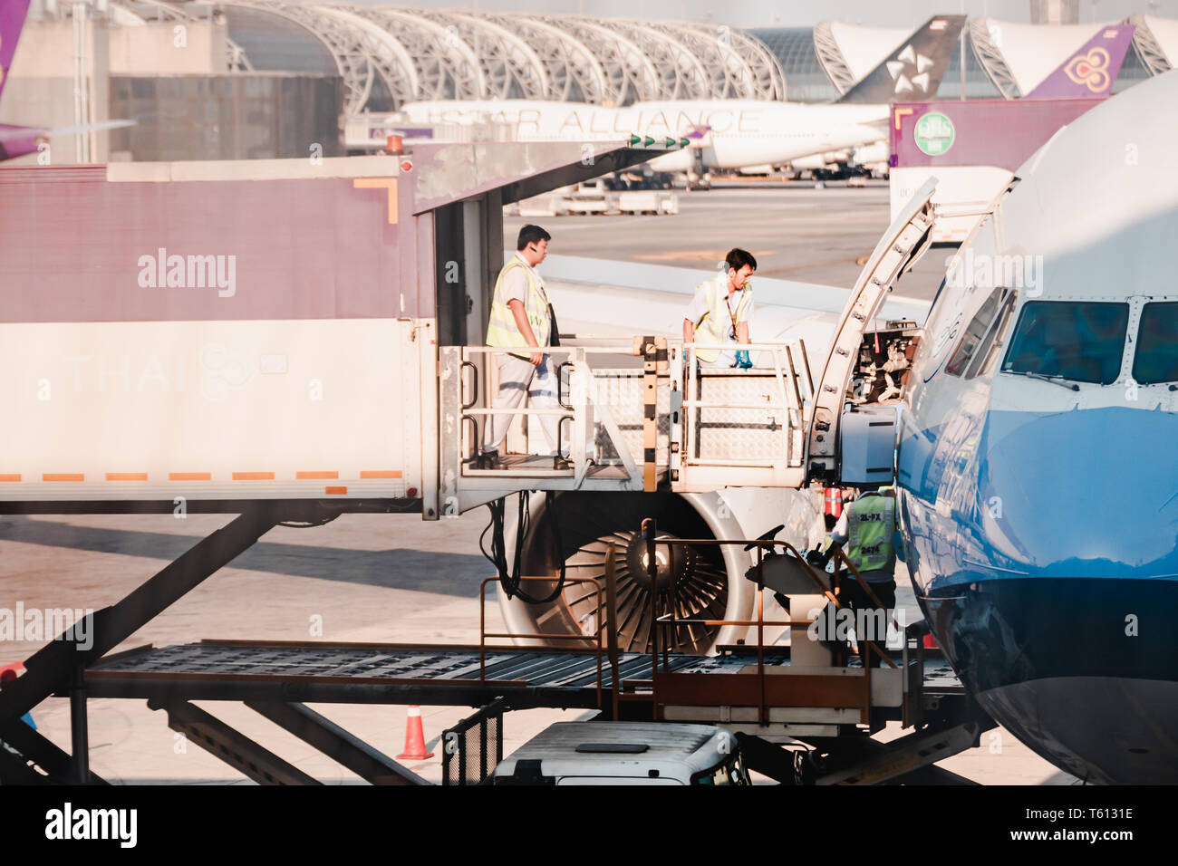 Asian ground crew loading food and supply into a departing aircraft ...