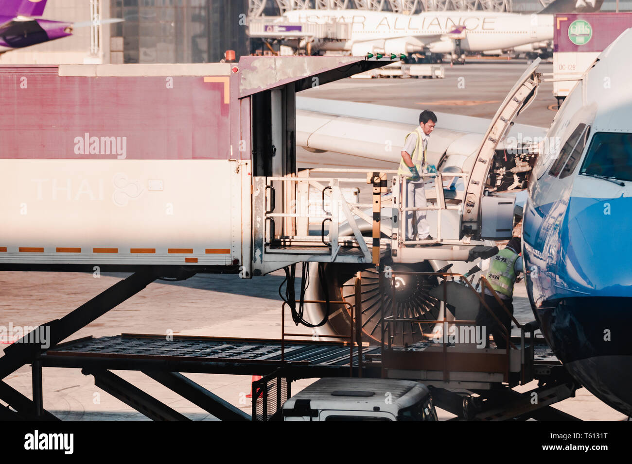 Asian ground crew loading food and supply into a departing aircraft ...