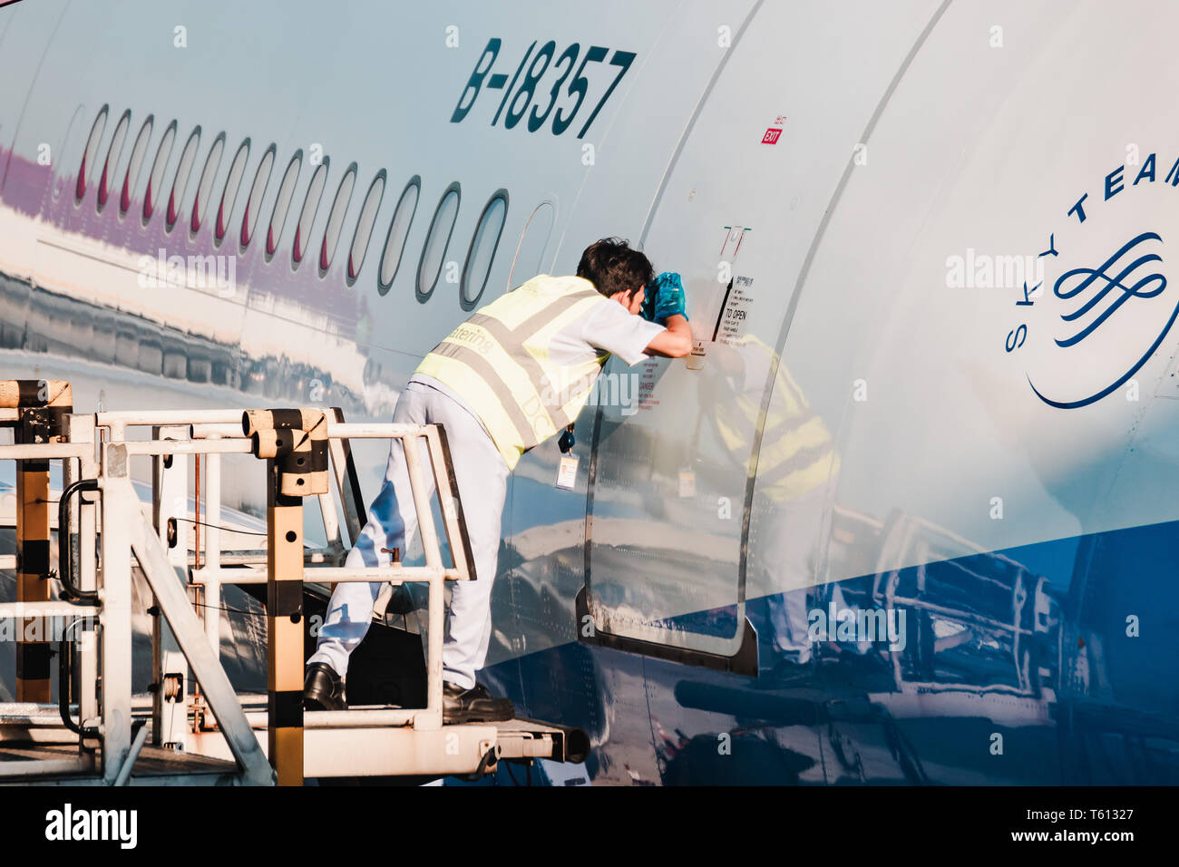 Asian ground crew looking through aircraft door windows to see if it's ...