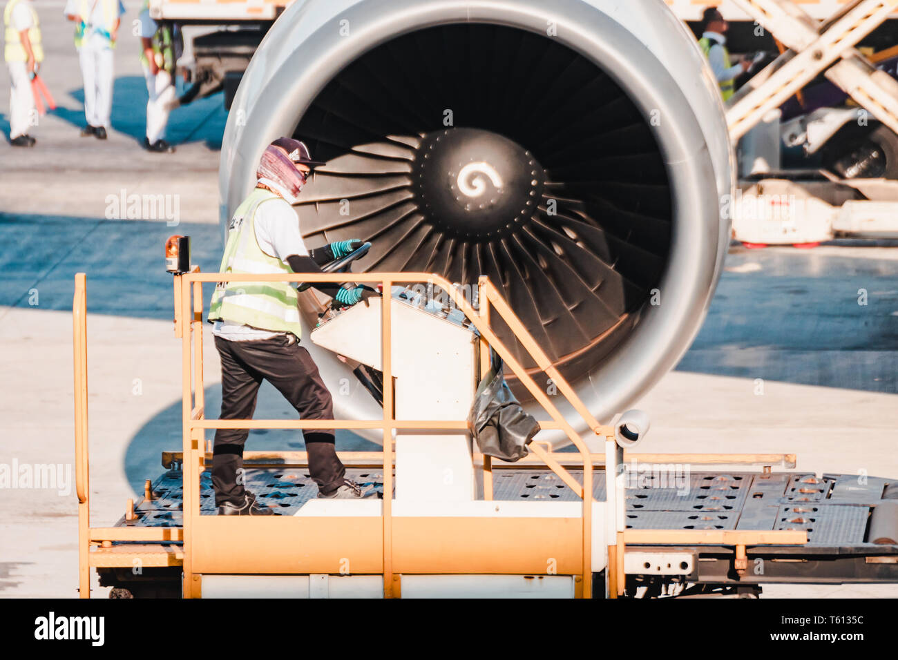 Asian ground crew raising elevated conveyor belt to load cargo into the ...