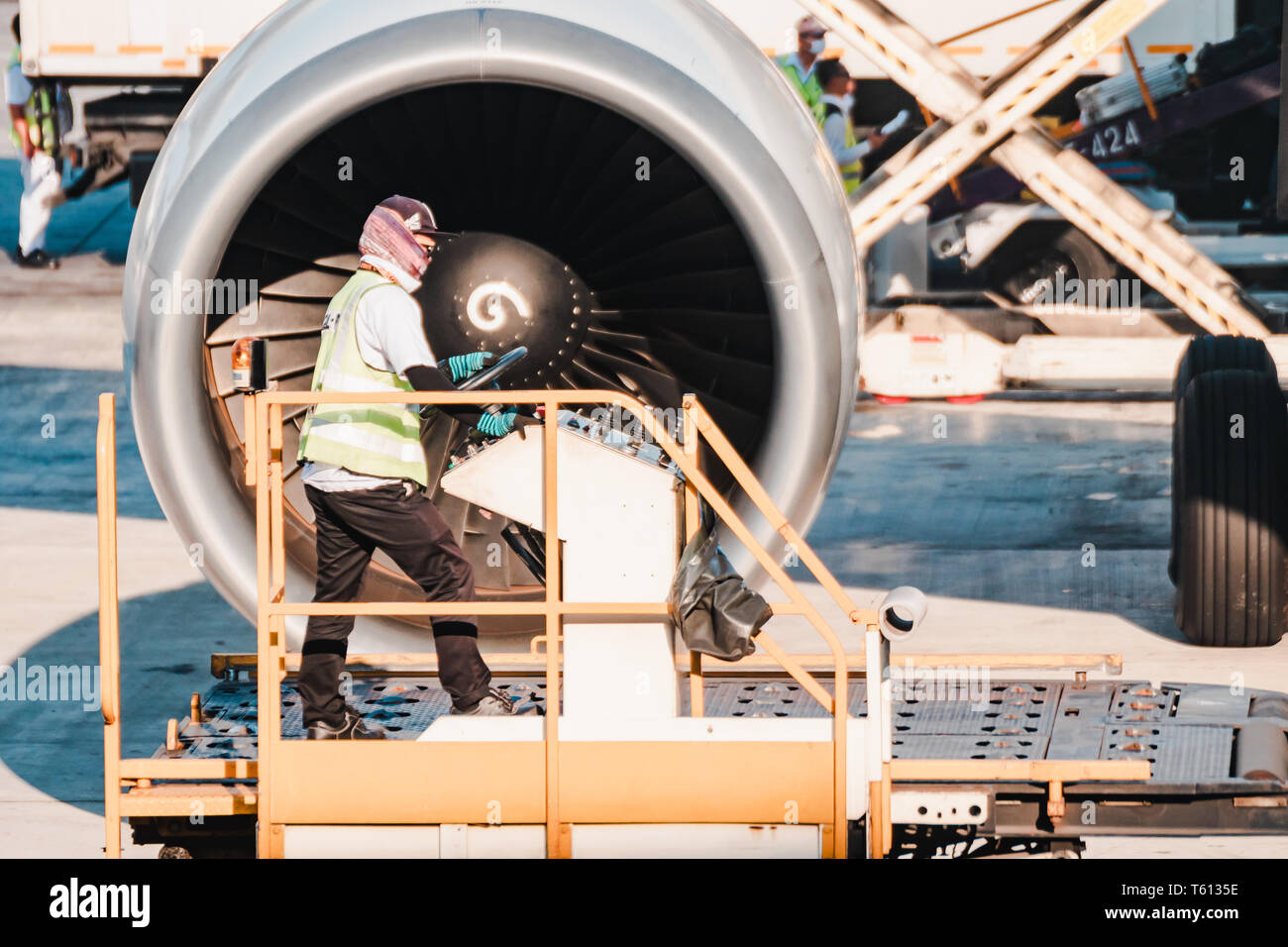 Asian ground crew raising elevated conveyor belt to load cargo into the ...
