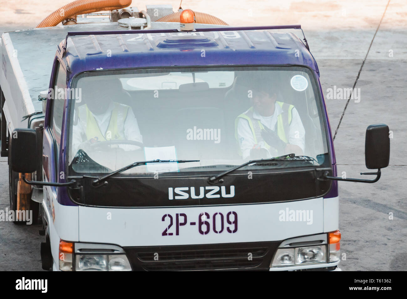 Two asian ground crew wearing vest driving a lavatory and water truck ...
