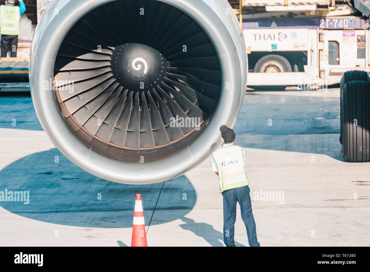 Asian ground crew perform a safety check on aircraft jet engine to make ...