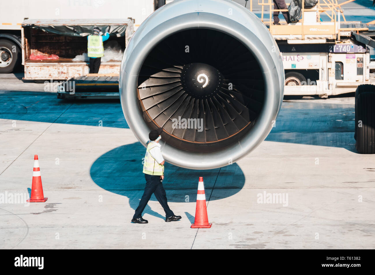 Asian ground crew perform a safety check on aircraft jet engine to make ...
