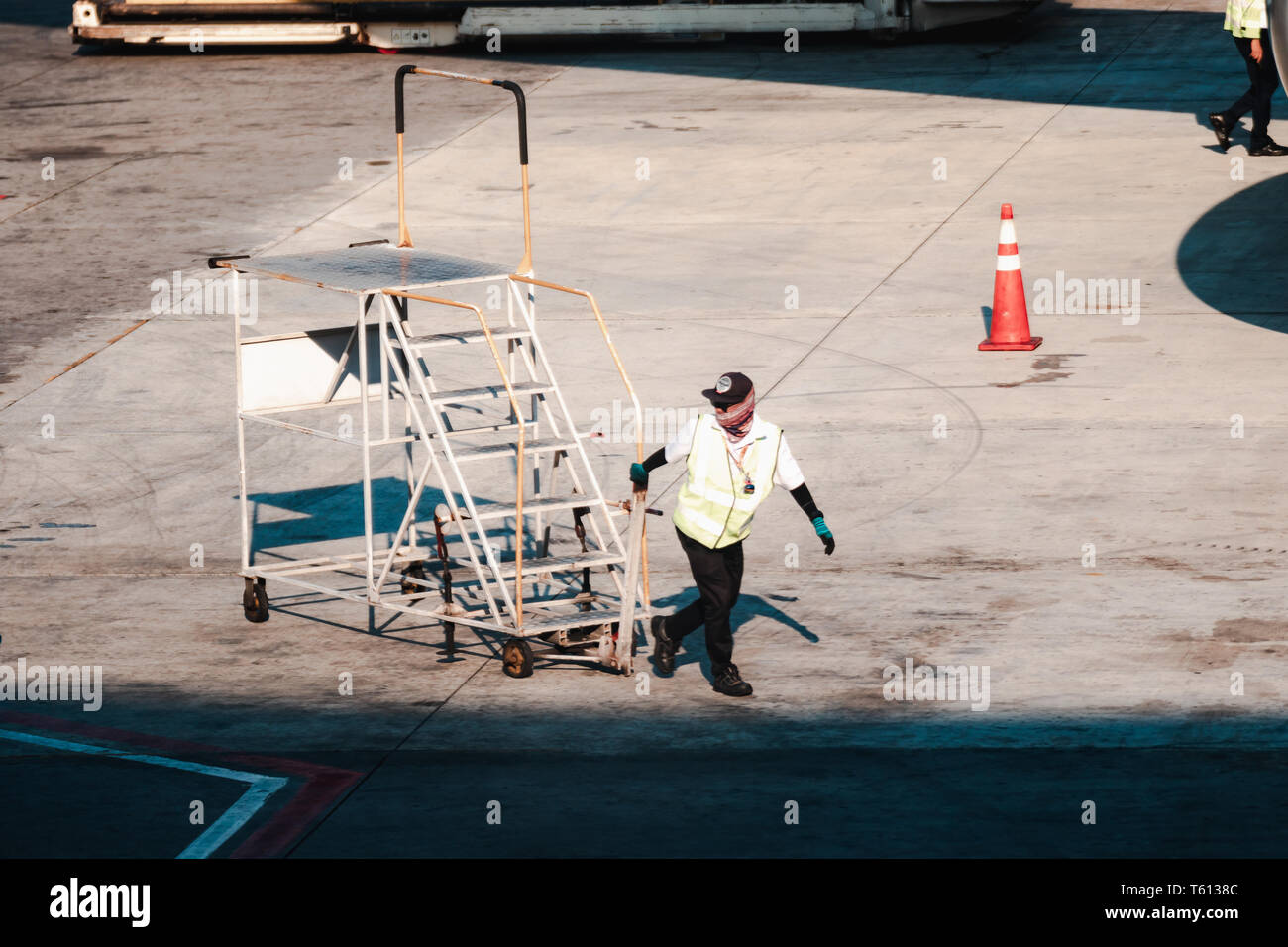 Asian ground crew dragging a stair to an aircraft to open the cargo bay ...
