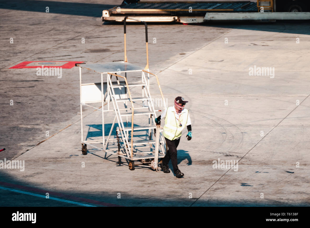 Asian ground crew dragging a stair to an aircraft to open the cargo bay ...
