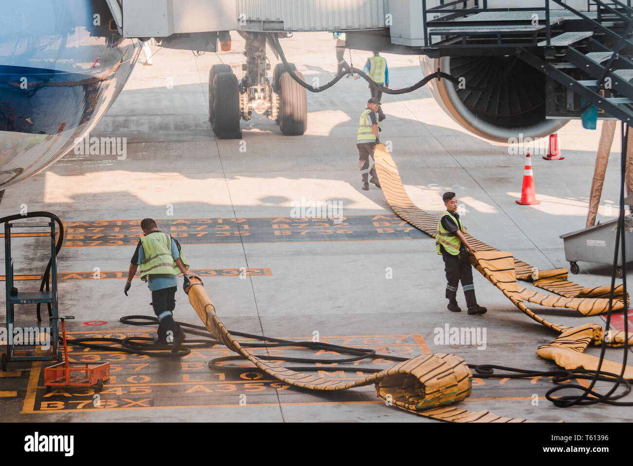Asian ground crew carrying yellow air conditioning ventilation pipe to ...