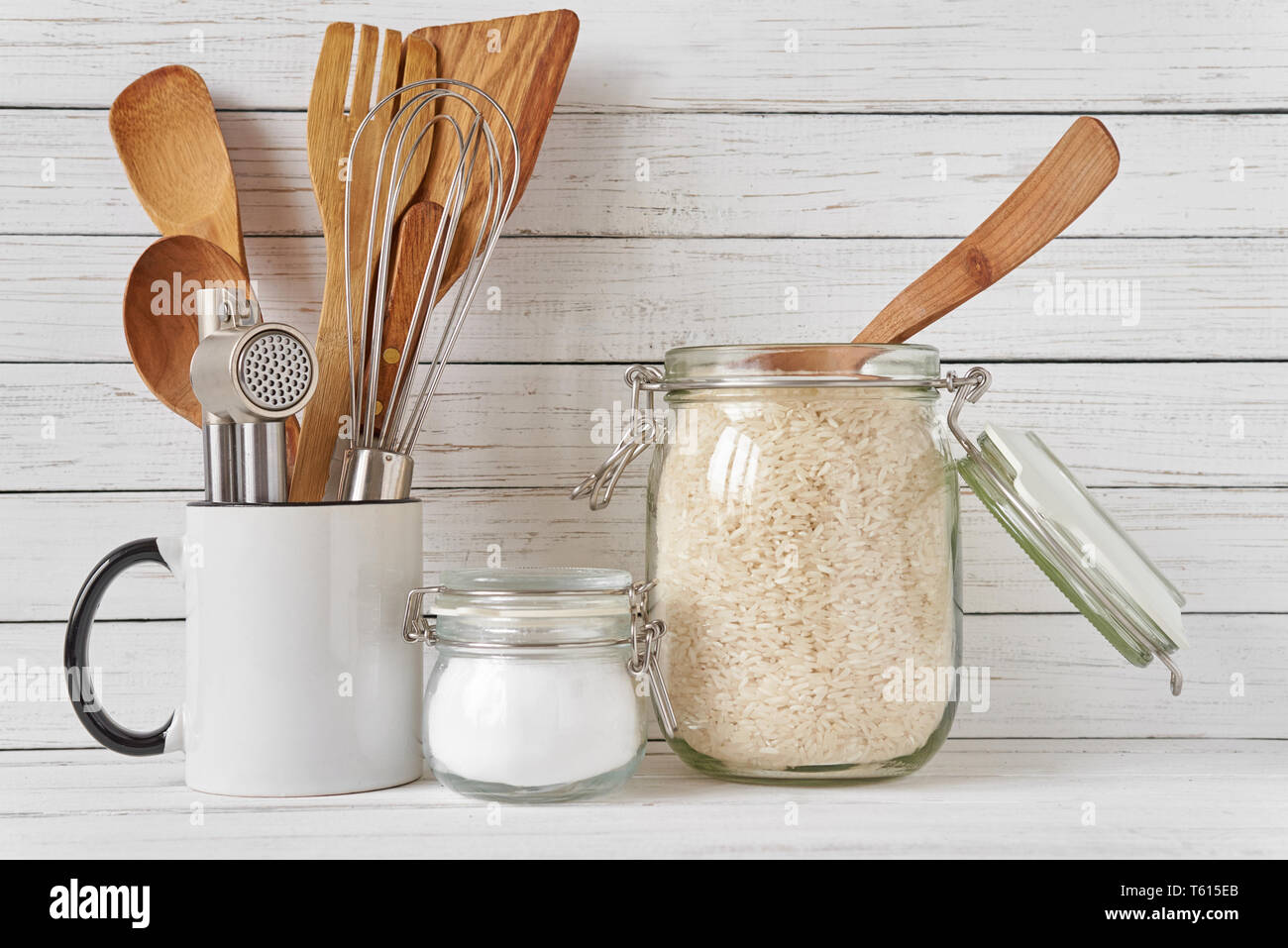 Kitchen tools and glass jar with rice on white table, front view ...